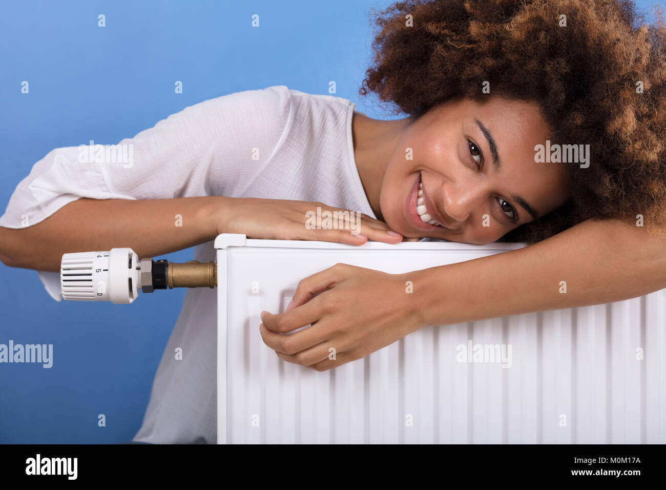 Portrait Of A Happy Young Woman Leaning On Heating Radiator Stock Photo ...