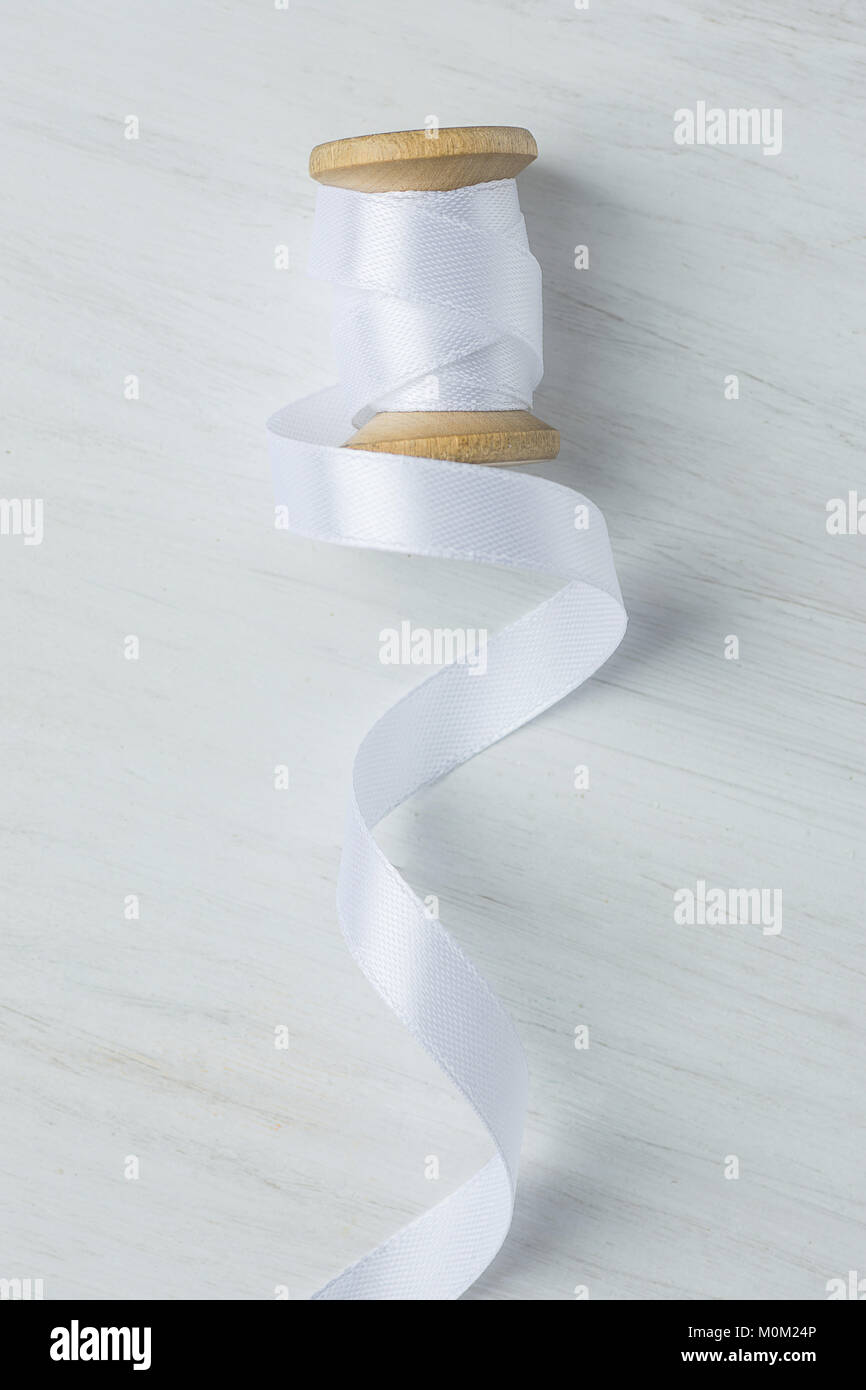 Single Wooden Spool Roll with Curly Silk Ribbon on White Wood ...