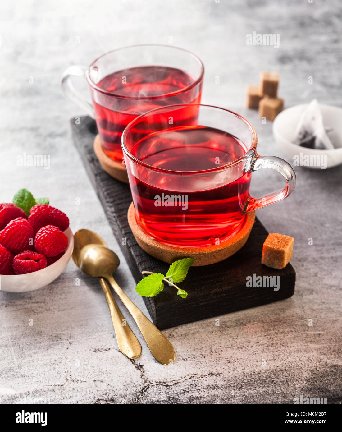 steaming hot raspberry tea in two transparent cups on a stone table ...