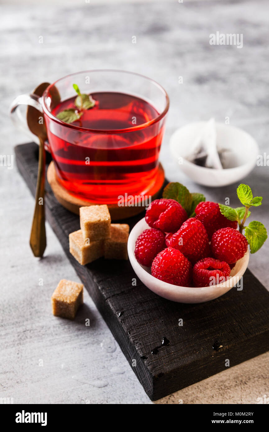 hot raspberry tea in transparent cup on a stone table. Fresh berries ...