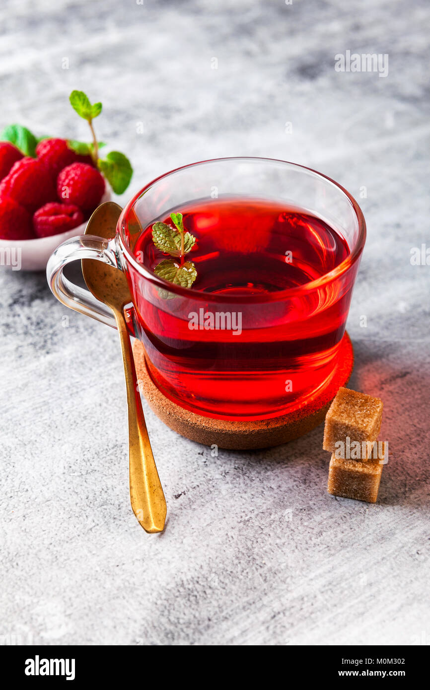 hot raspberry tea in transparent cup on a stone table. Fresh berries ...