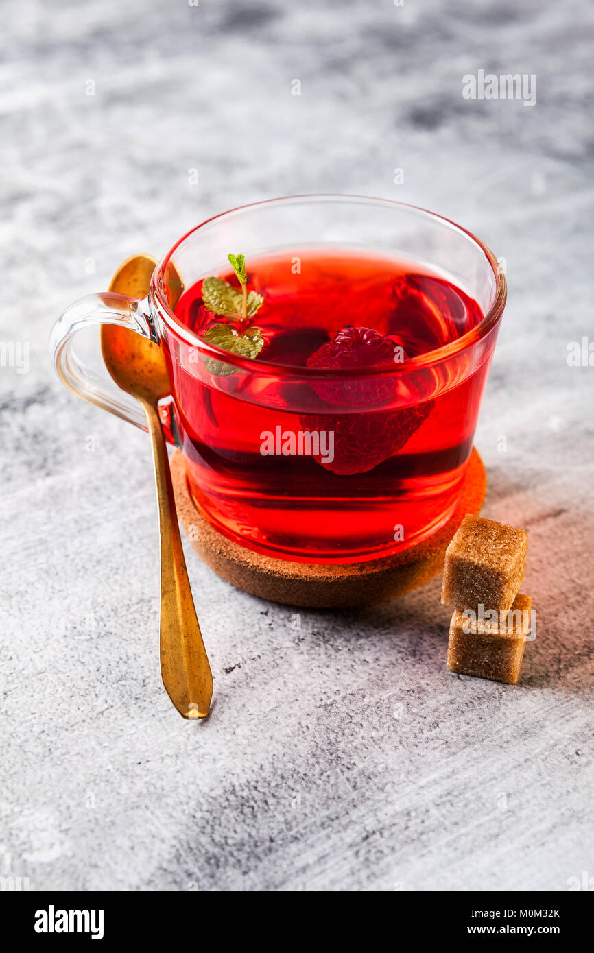 hot raspberry tea in transparent cup on a stone table. Fresh berries ...
