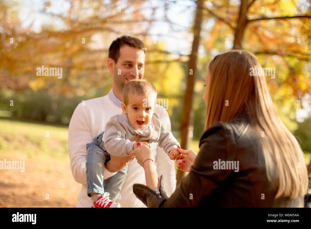Happy young parents have fun with baby boy in autumn park Stock Photo ...
