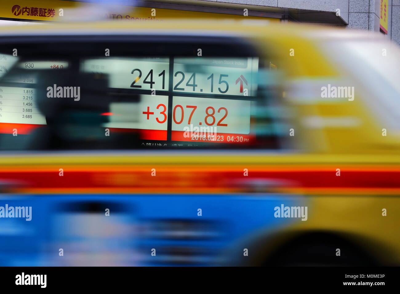 A taxi passes an electronic sign board showing Japan's Nikkei Stock ...