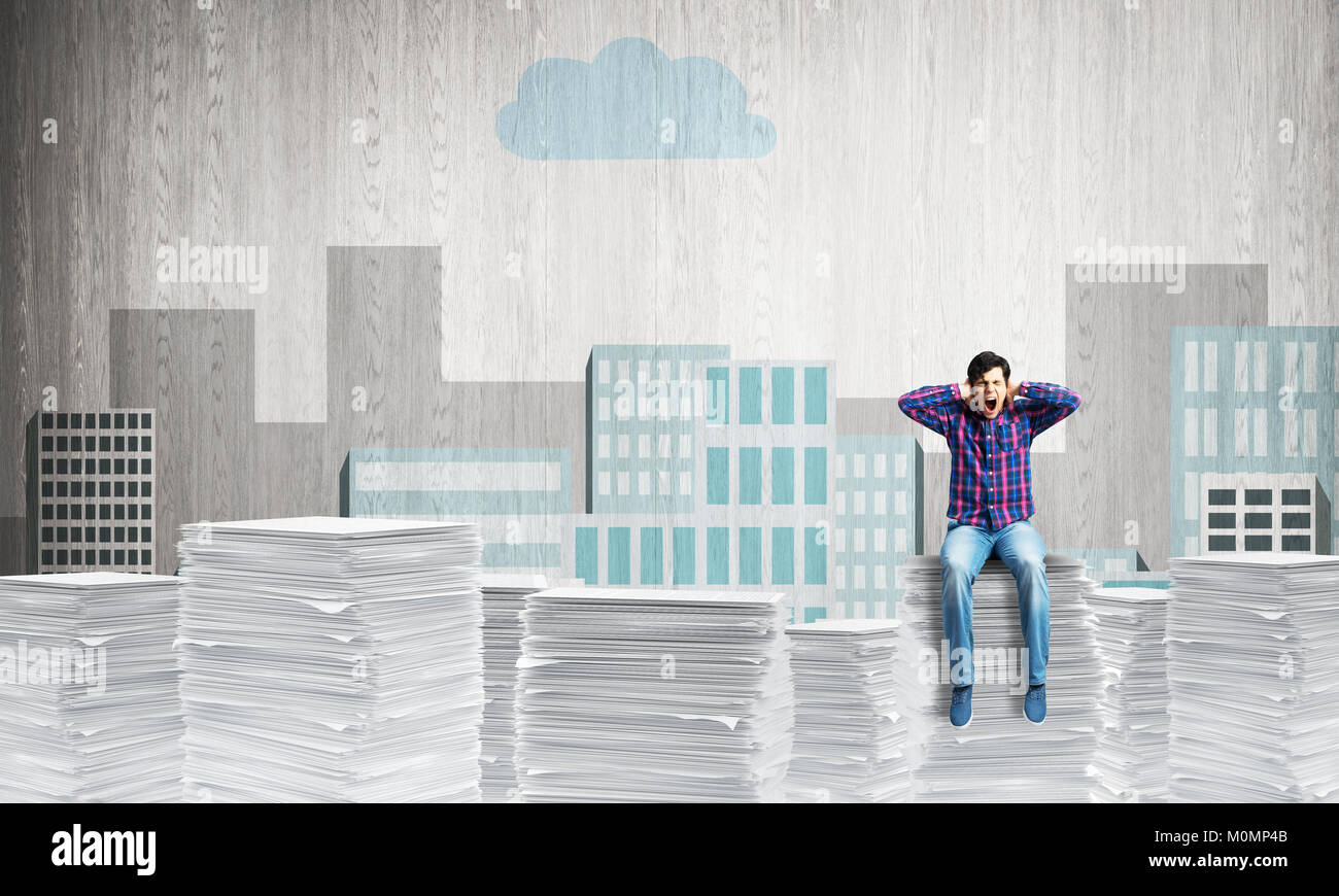 Young man sitting on pile of paper documents Stock Photo - Alamy
