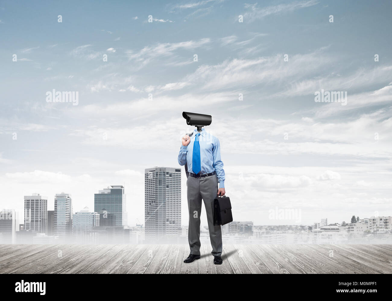 Camera headed man standing on wooden floor against modern cityscape ...