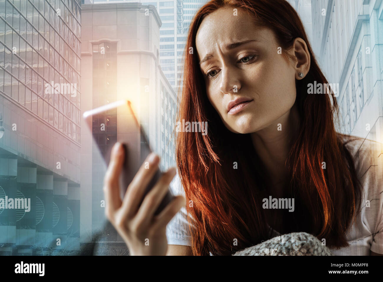 Sad young woman sitting and using the cellphone Stock Photo - Alamy