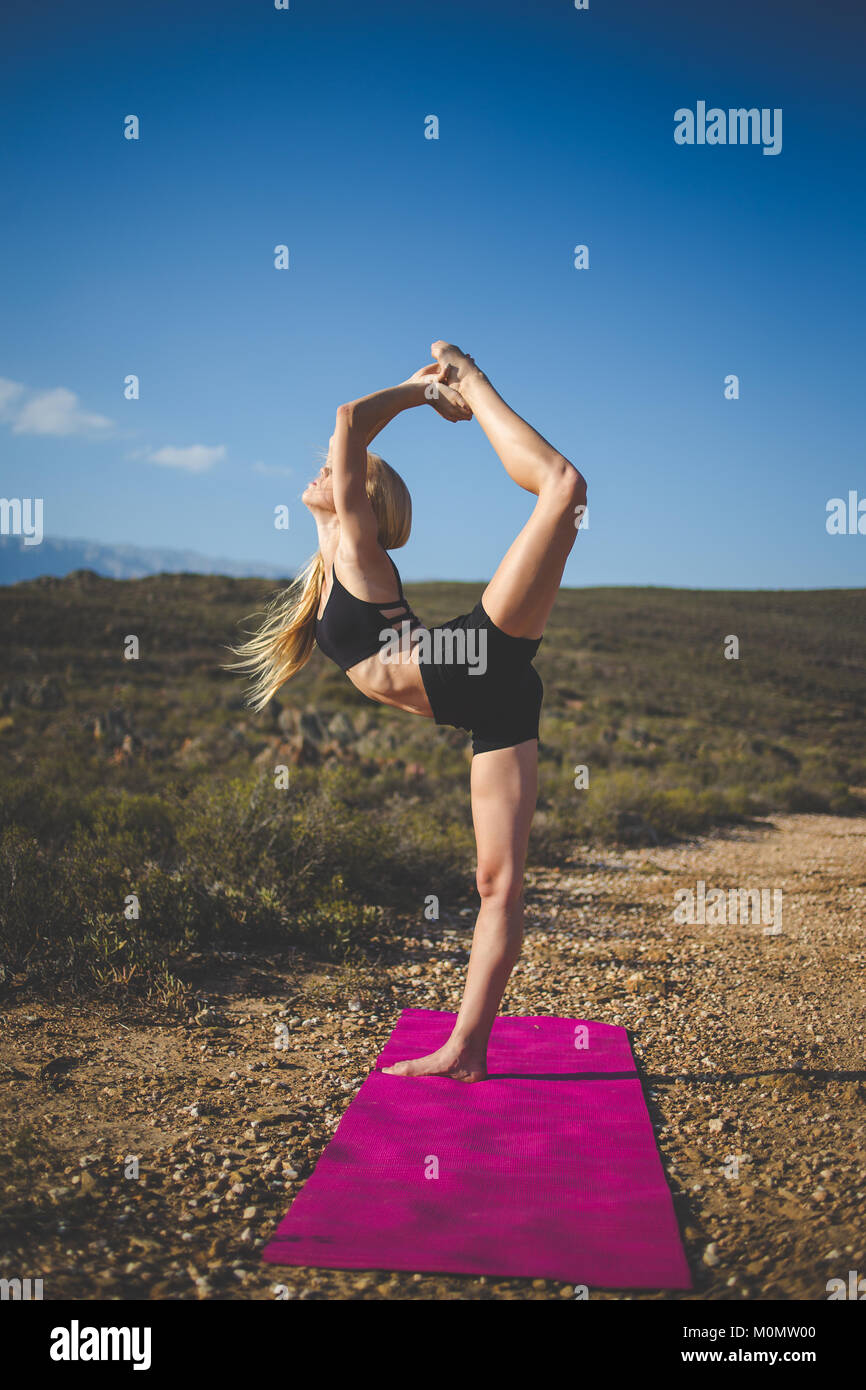Female model practicing yoga in the outdoors doing stretching and ...