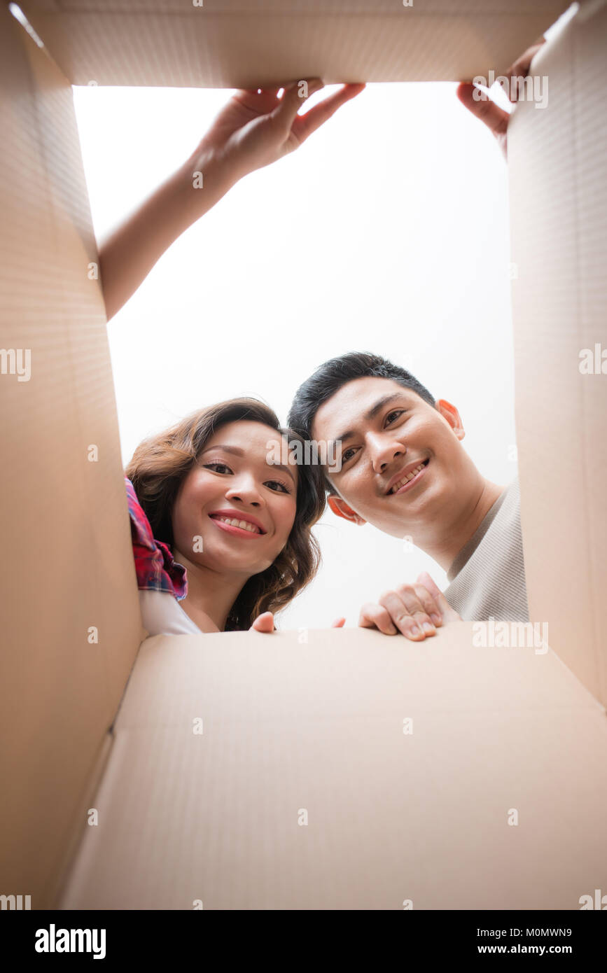 Smiling young couple opening a carton box and looking inside Stock ...
