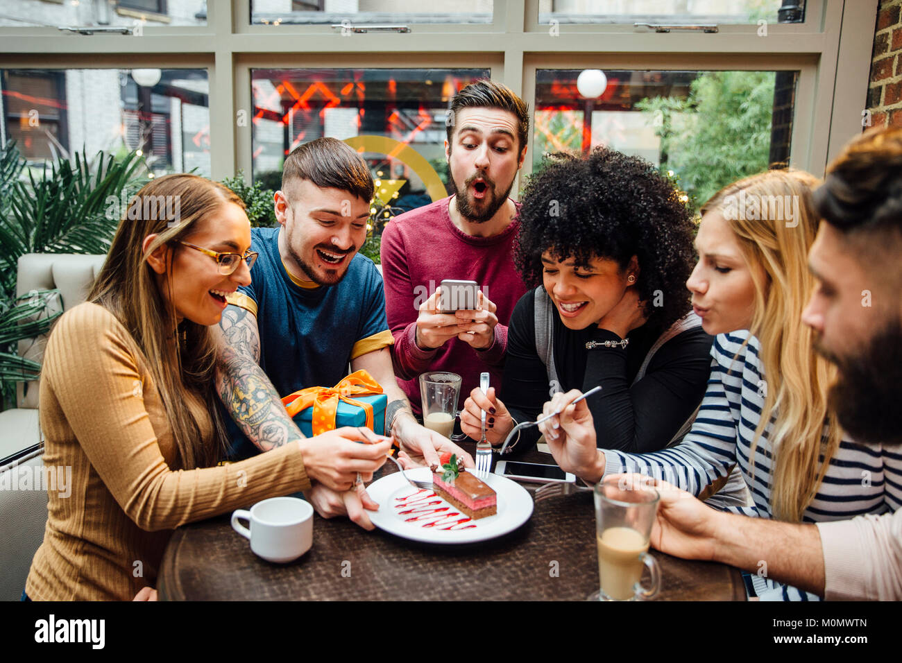 Group of friends are sharing a slice of cake at a birthday party. One ...