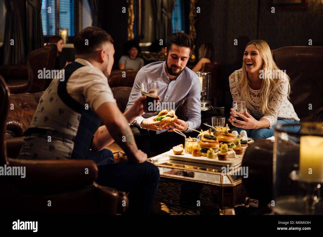 FRiends are enjoying drinks and food in a bar/restaurant. They are ...