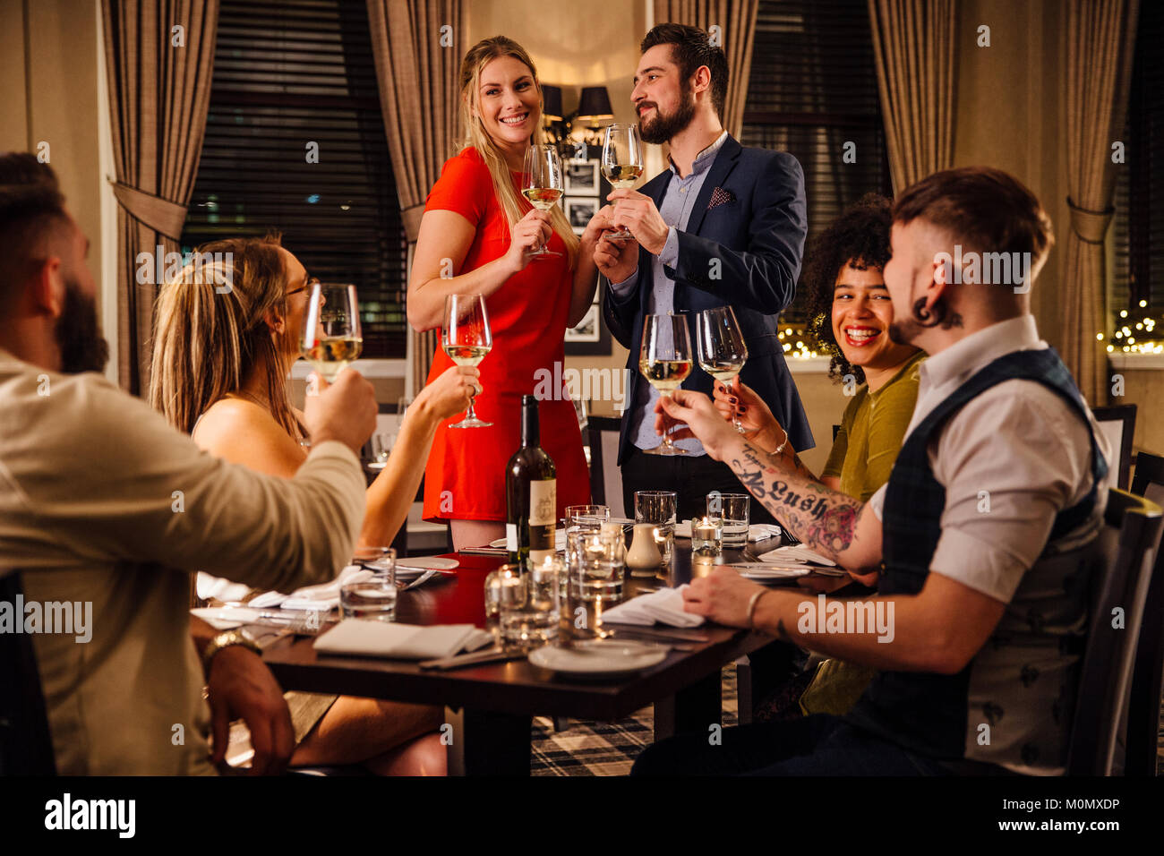 Friends are at a formal meal together. A couple are standing together ...