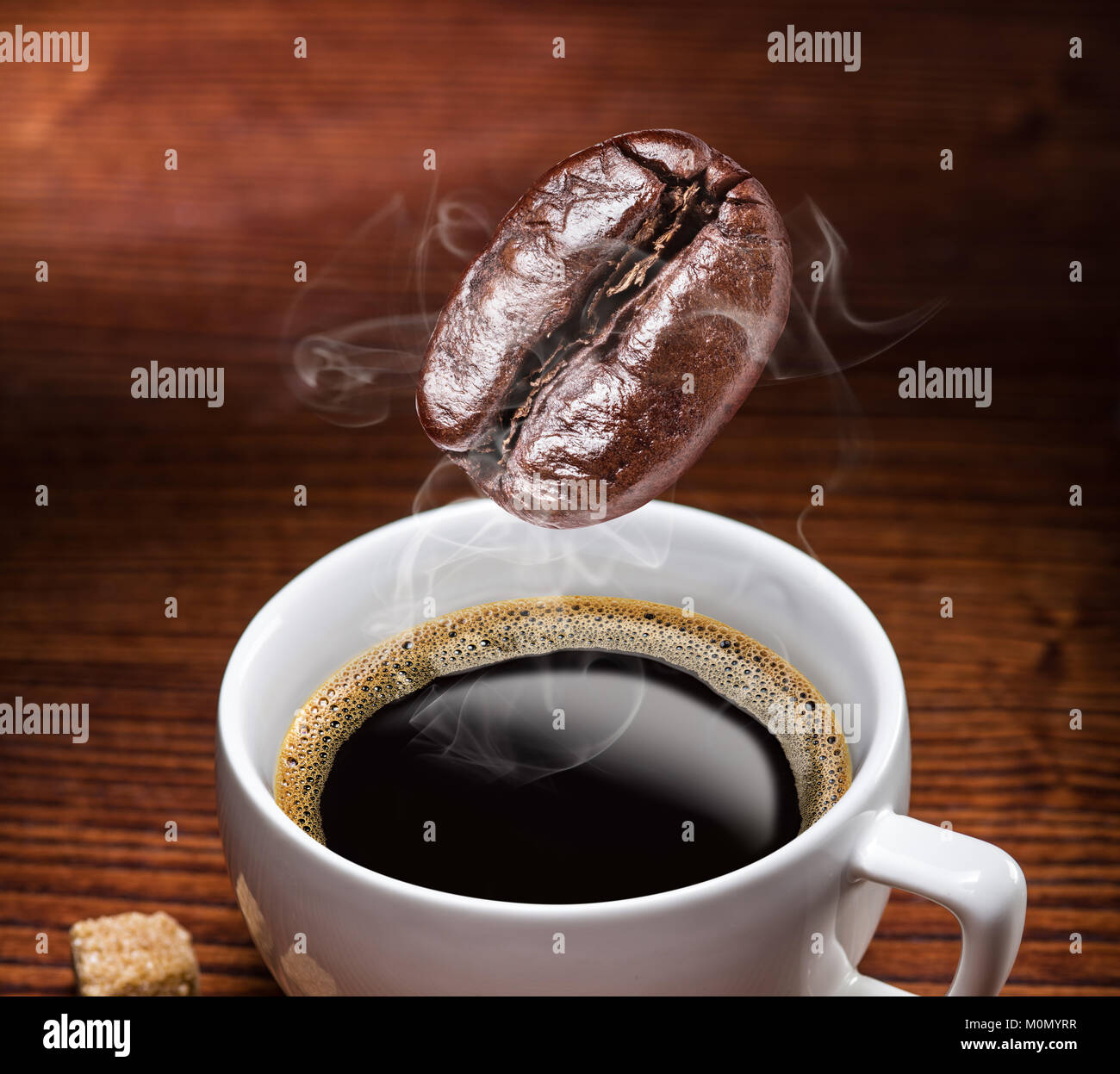 Roasted coffee bean falling into the cup of coffee. Conceptual picture ...