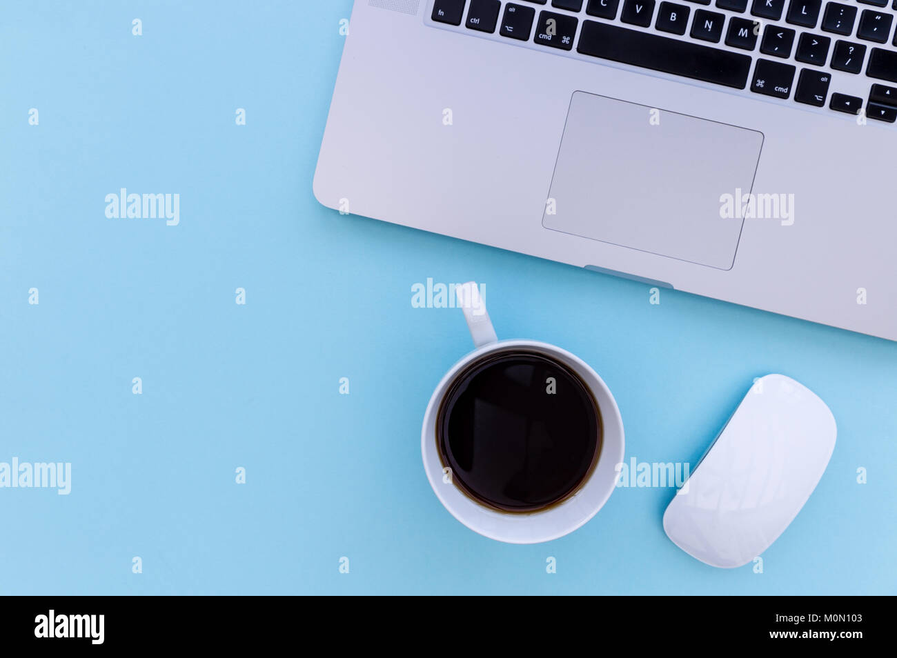 Laptop computer keyboard coffee and mouse overhead on bright blue ...