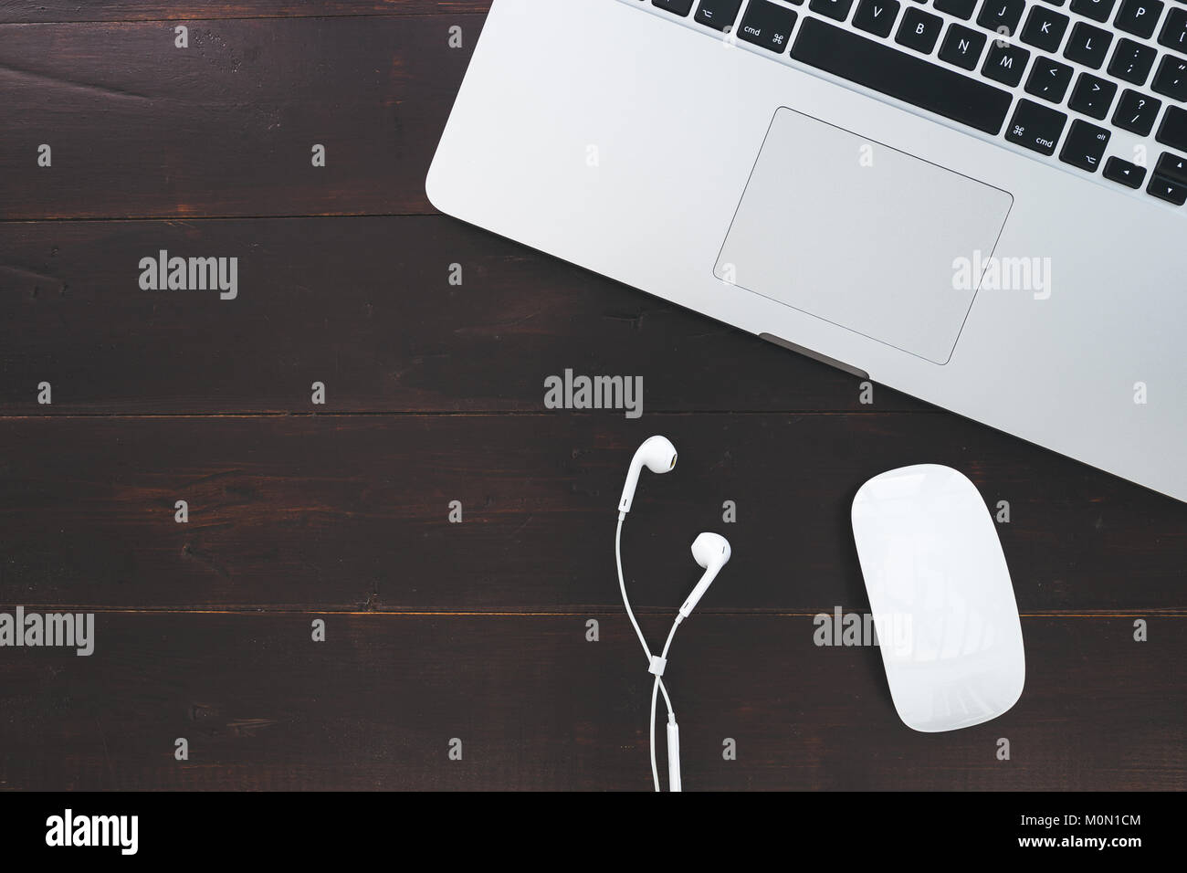 Laptop computer keyboard mouse and music earphones overhead on dark ...