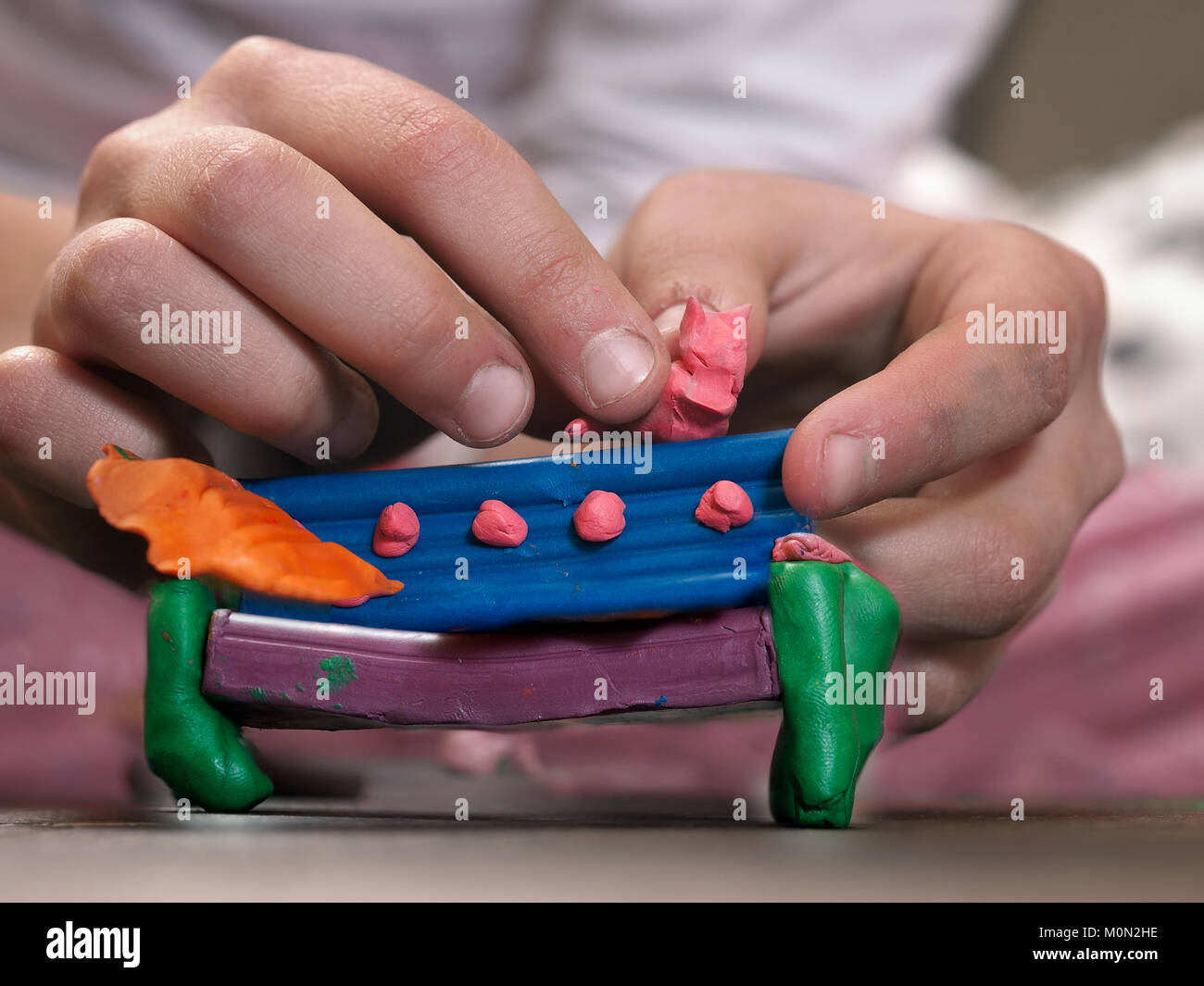 Hands of a small child of play plasticine. Is sculptured the figure of ...
