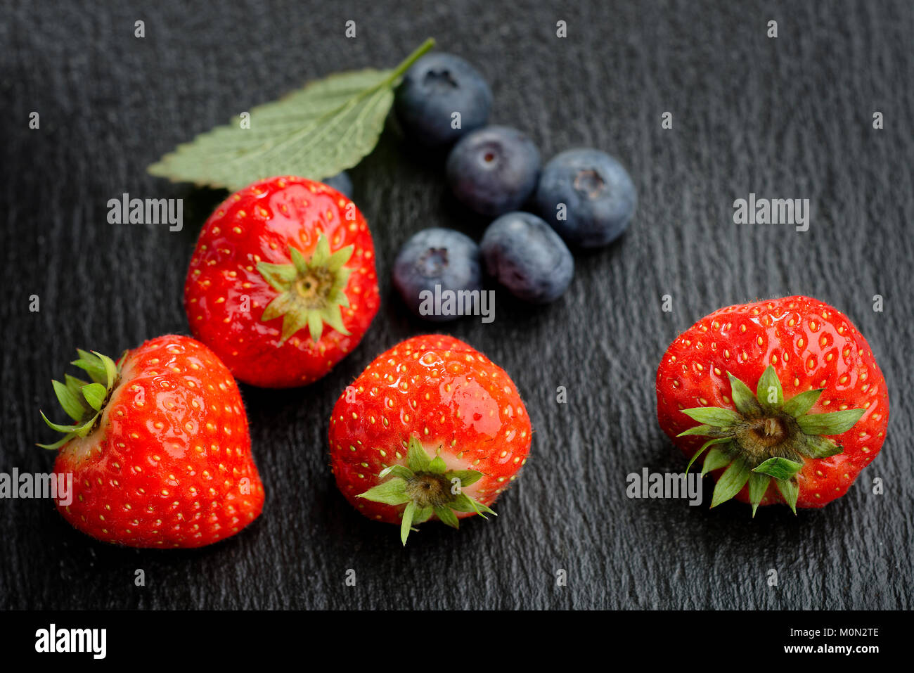 Strawberries and blueberries on a black background Stock Photo - Alamy