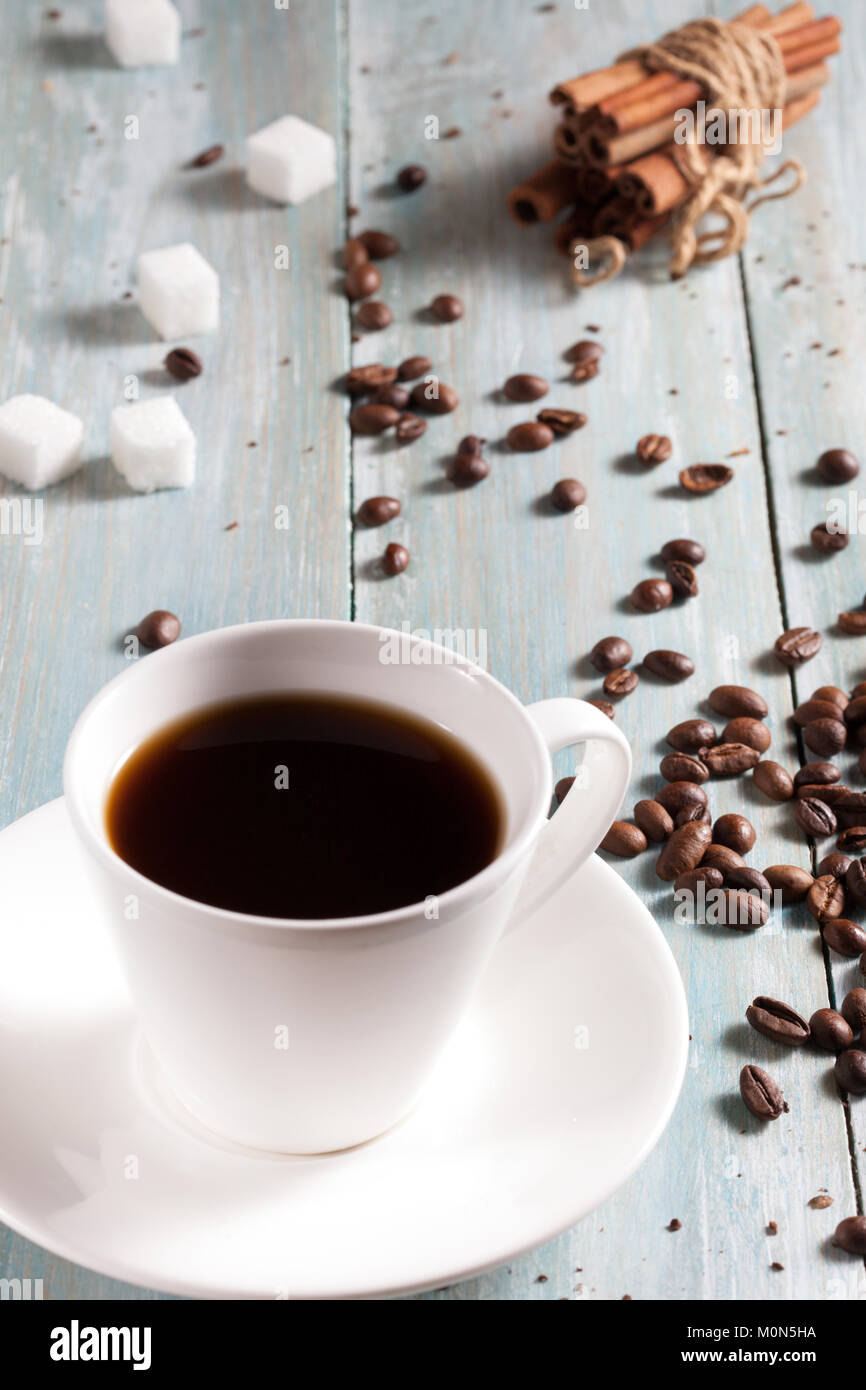 A cup of coffee with sprinkled lump sugar and a bunch of cinnamon on ...