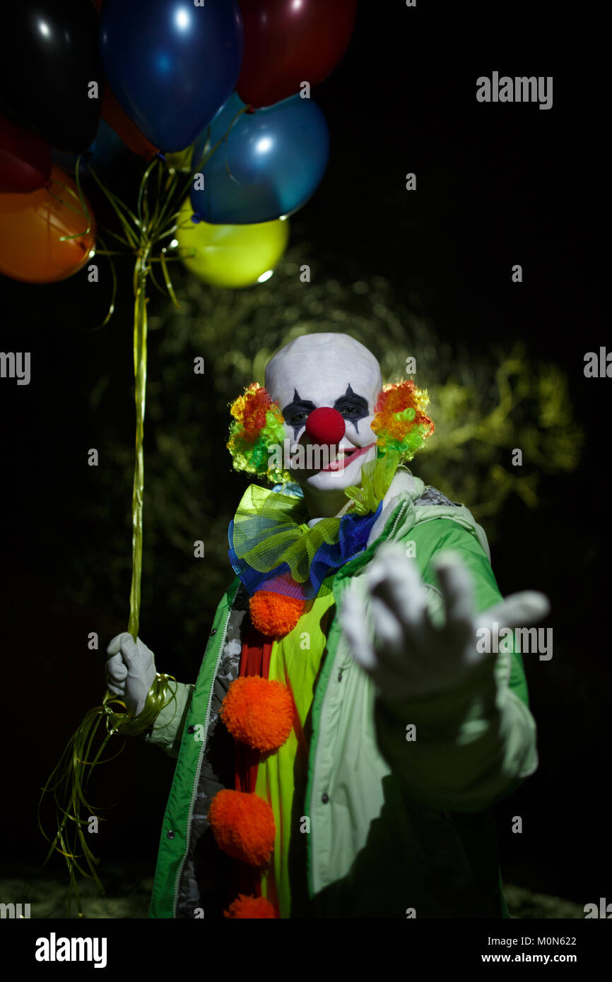 Photo of smiling clown with colorful balloons at night in street Stock ...