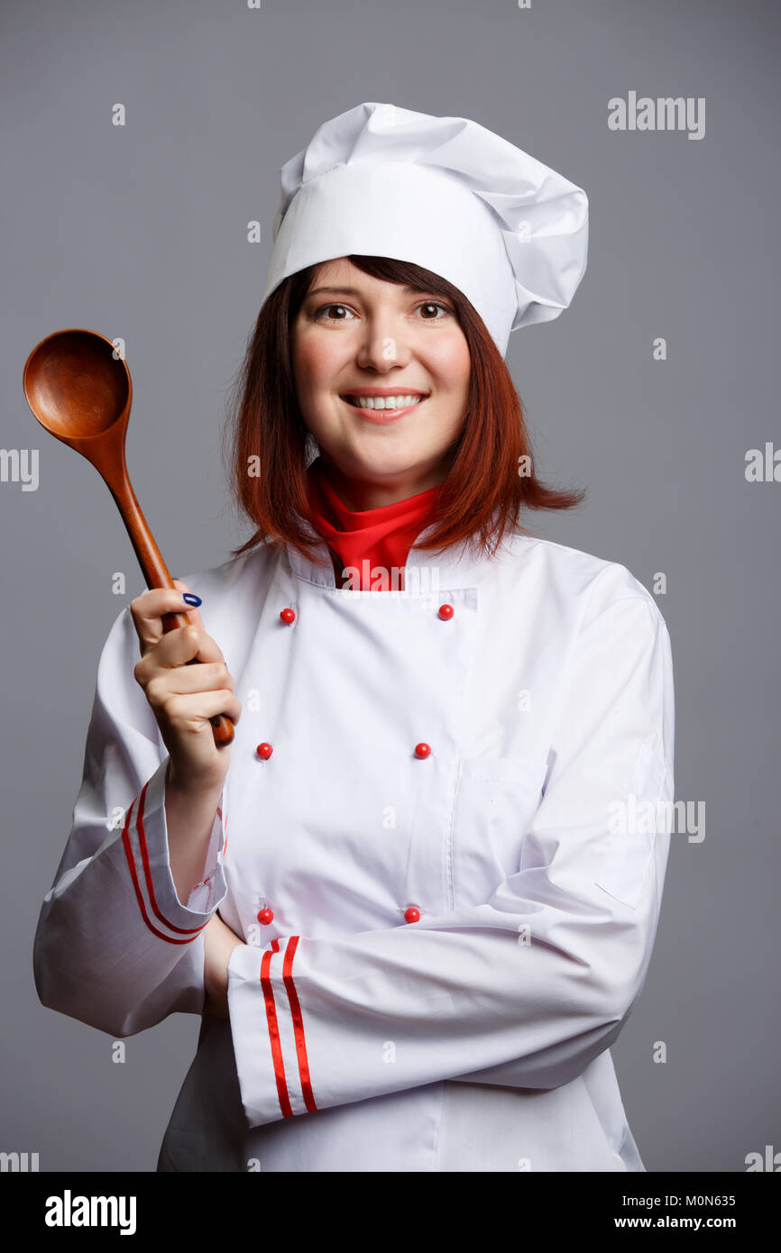 Photo of cook girl in white dressing-gown and cap with wooden spoon ...