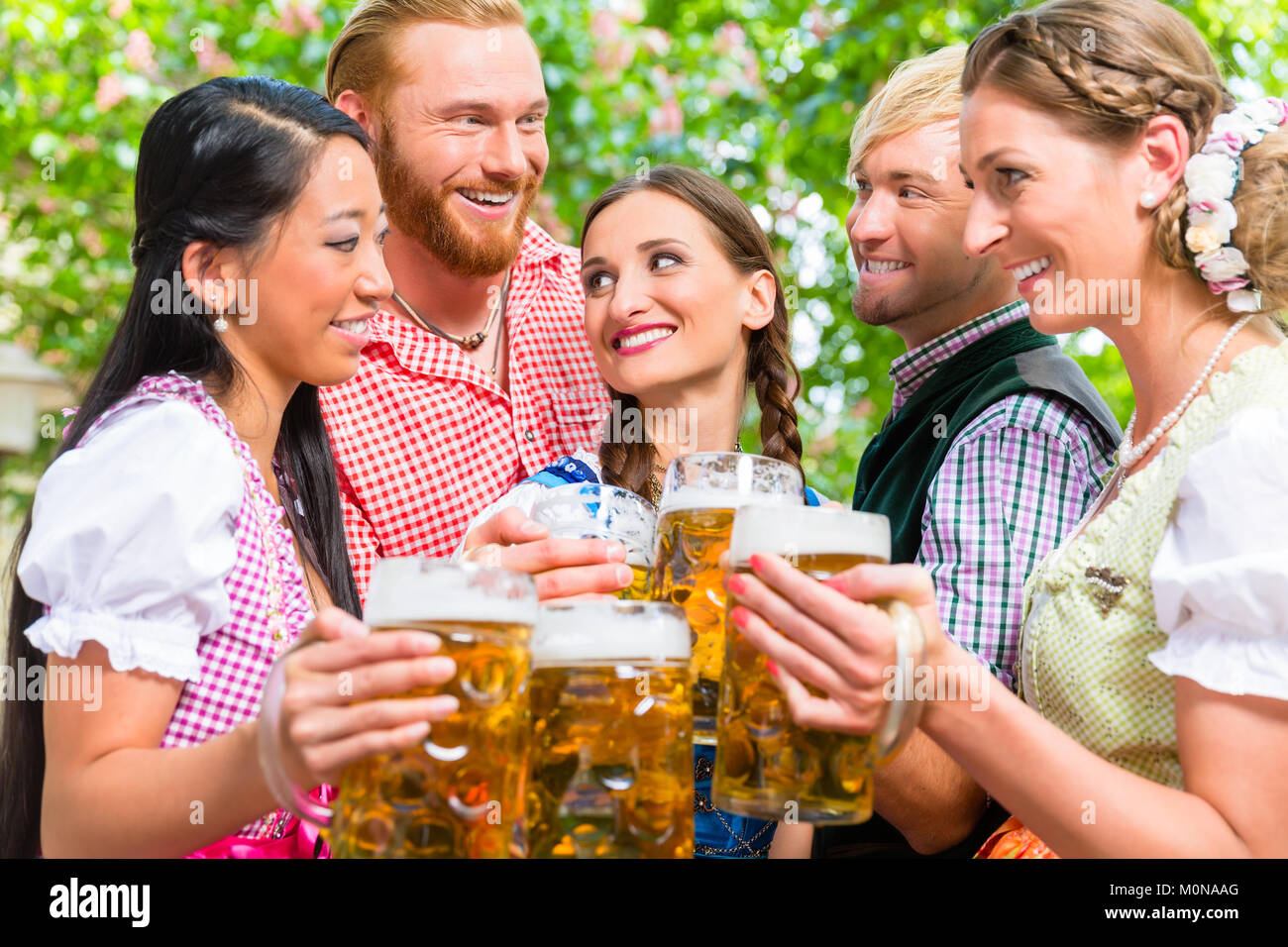 Friends having fun in beer garden while clinking glasses Stock Photo ...