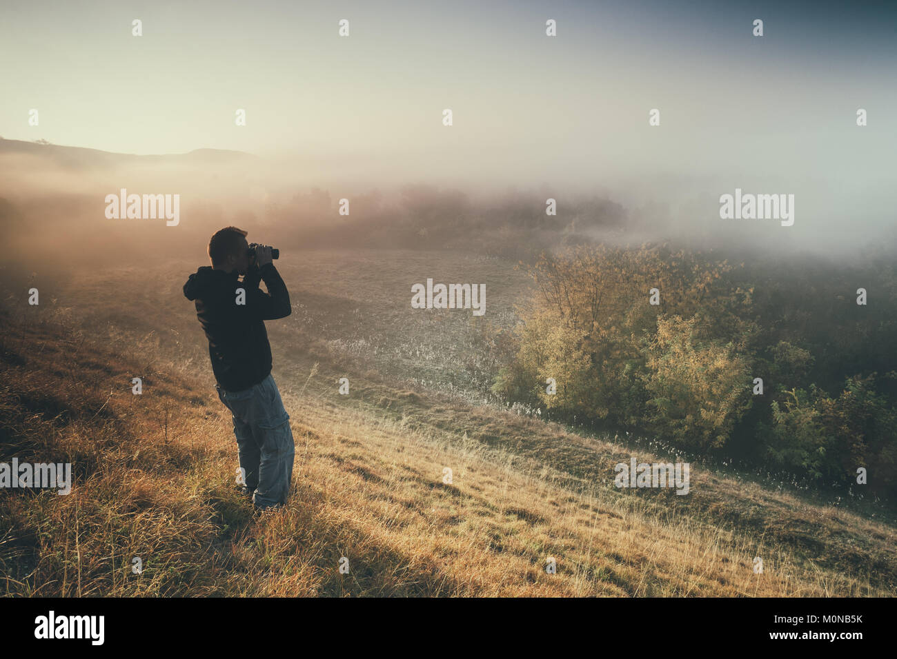 Man is hiking and watching nature with binoculars in the morning Stock ...