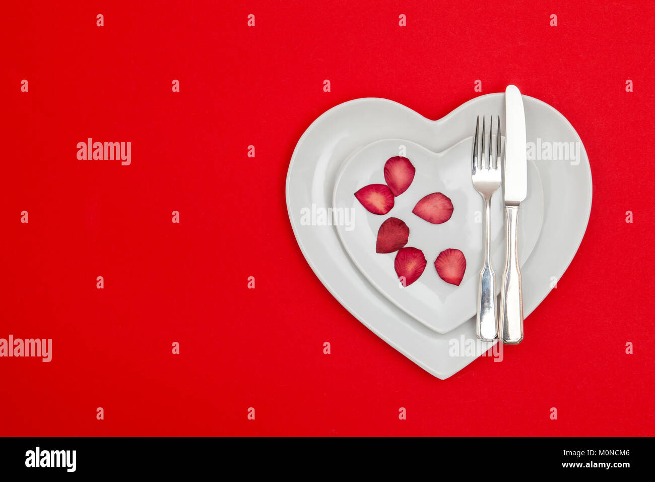 Heart shaped plate with knife and fork on a red background Stock Photo ...