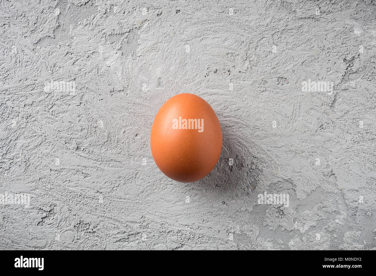 One beige egg on gray stone background Concept Food is loneliness ...