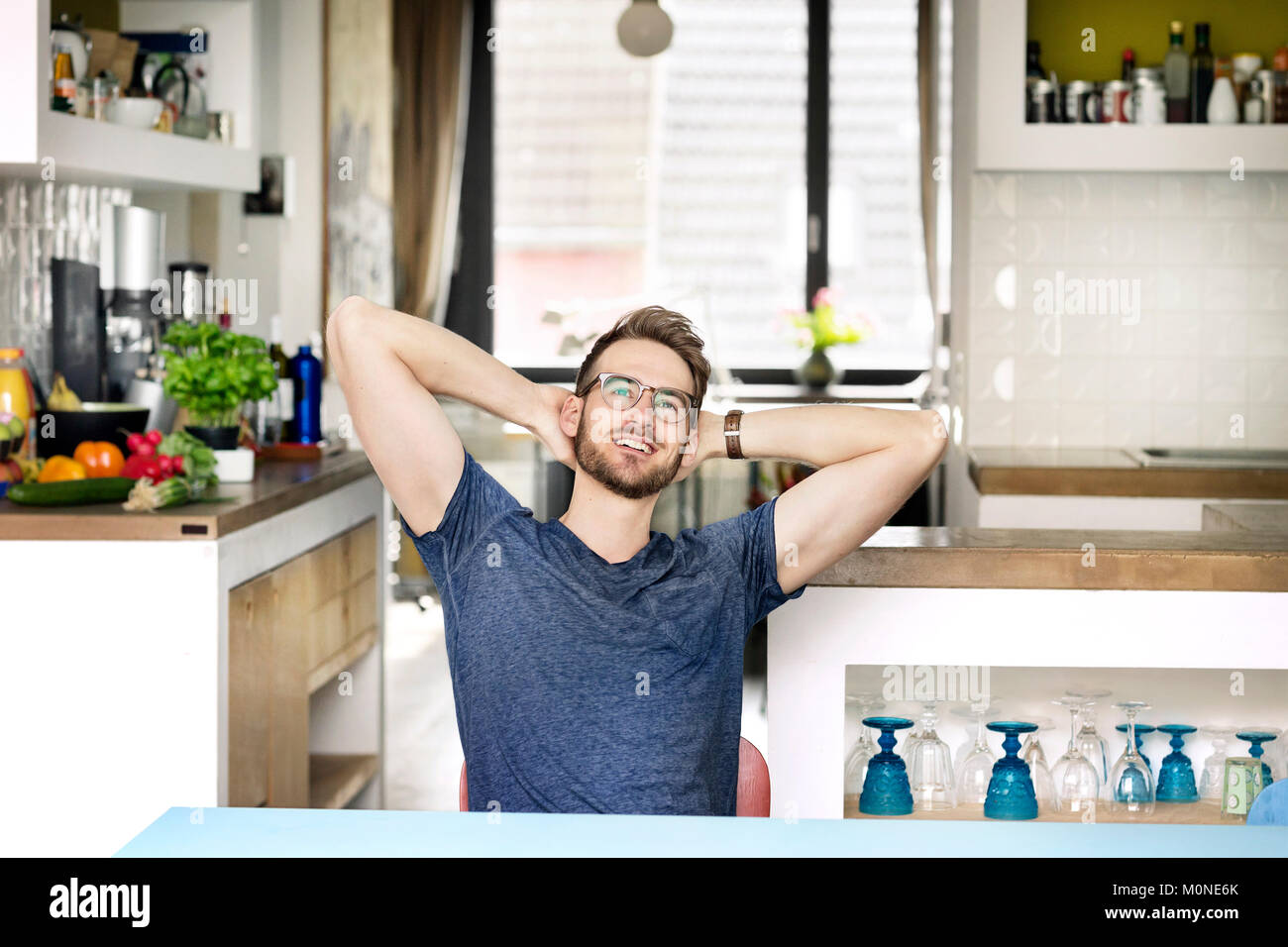 Portrait of smiling young man sitting at kitchen table at home Stock ...