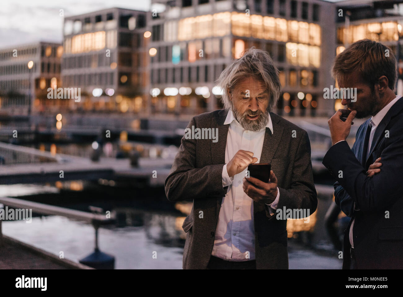 Two businessmen city looking cell phone hi-res stock photography and ...