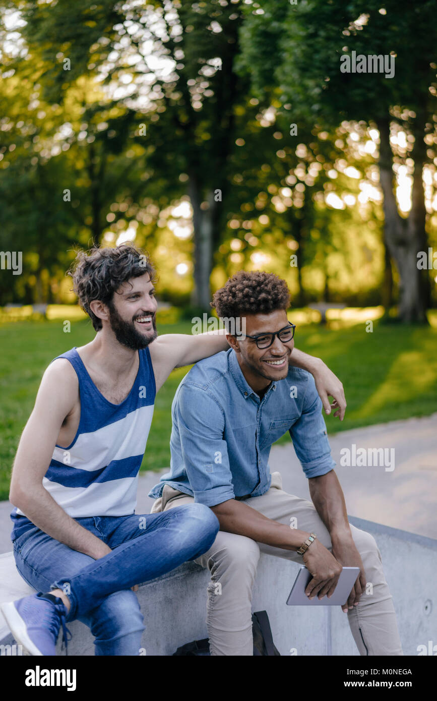 Two happy friends sitting in a skatepark Stock Photo - Alamy