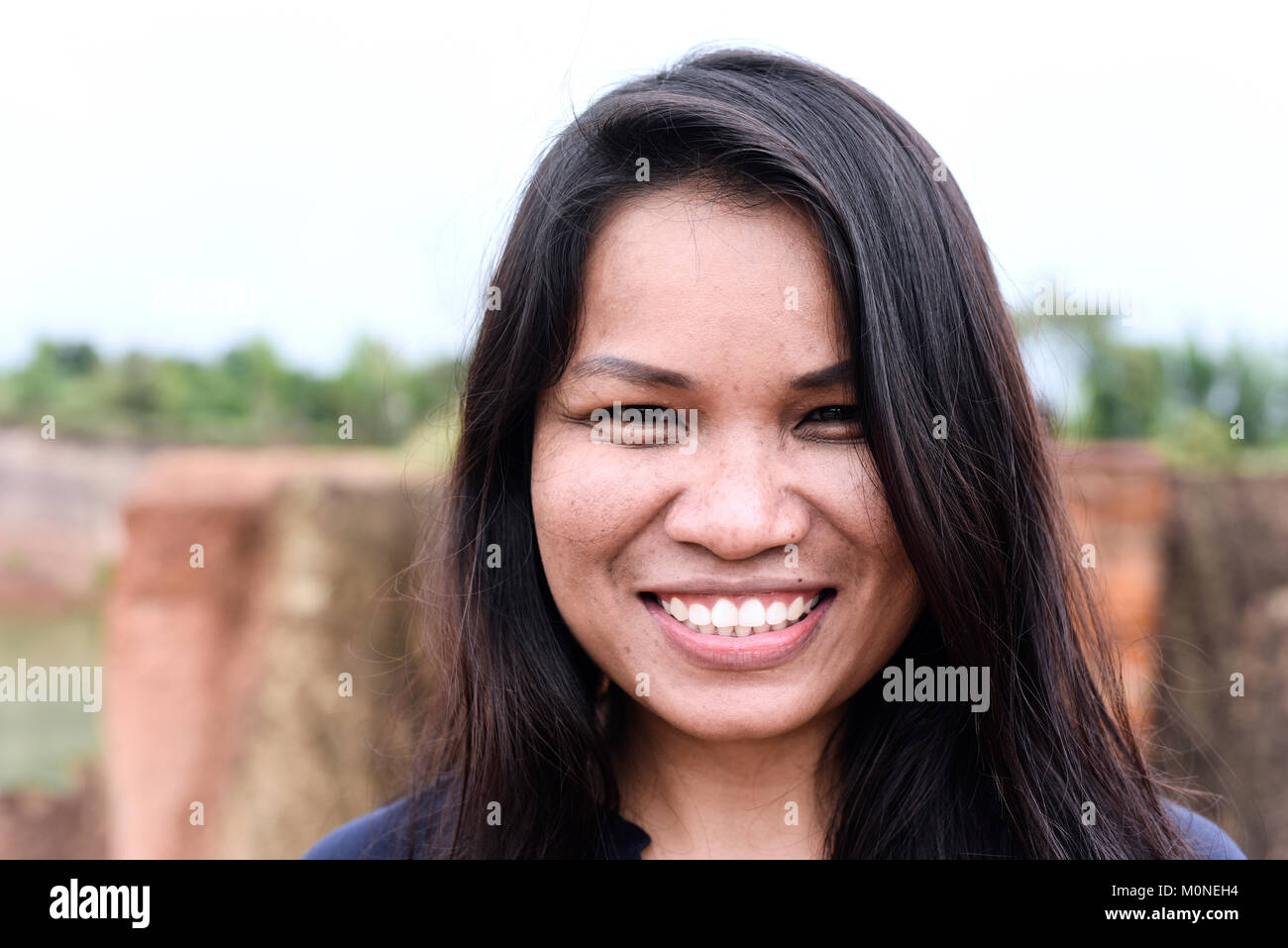 Portrait of a pretty asian millennial woman smiling at camera outdoors ...