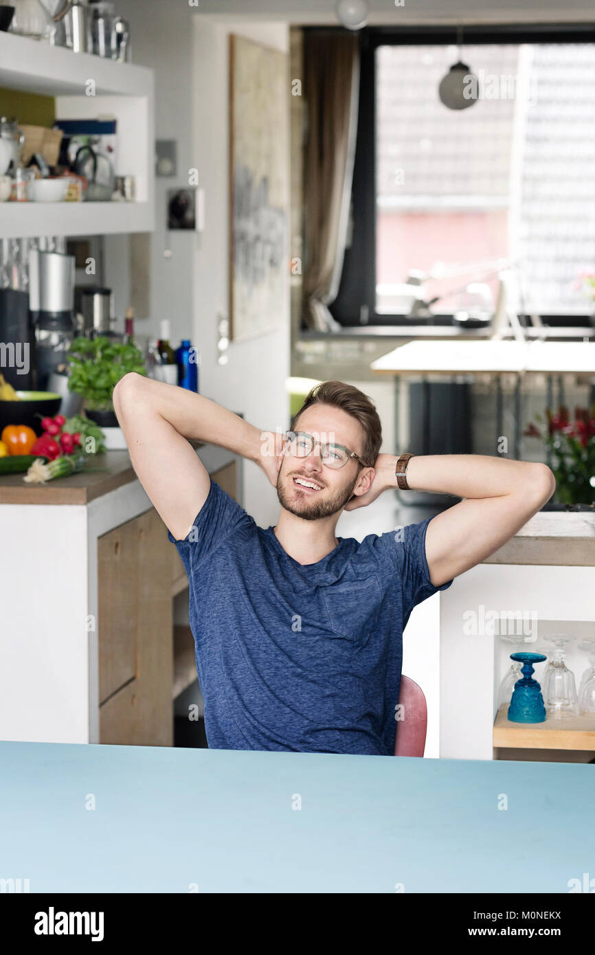 Portrait of smiling young man sitting at kitchen table at home Stock ...