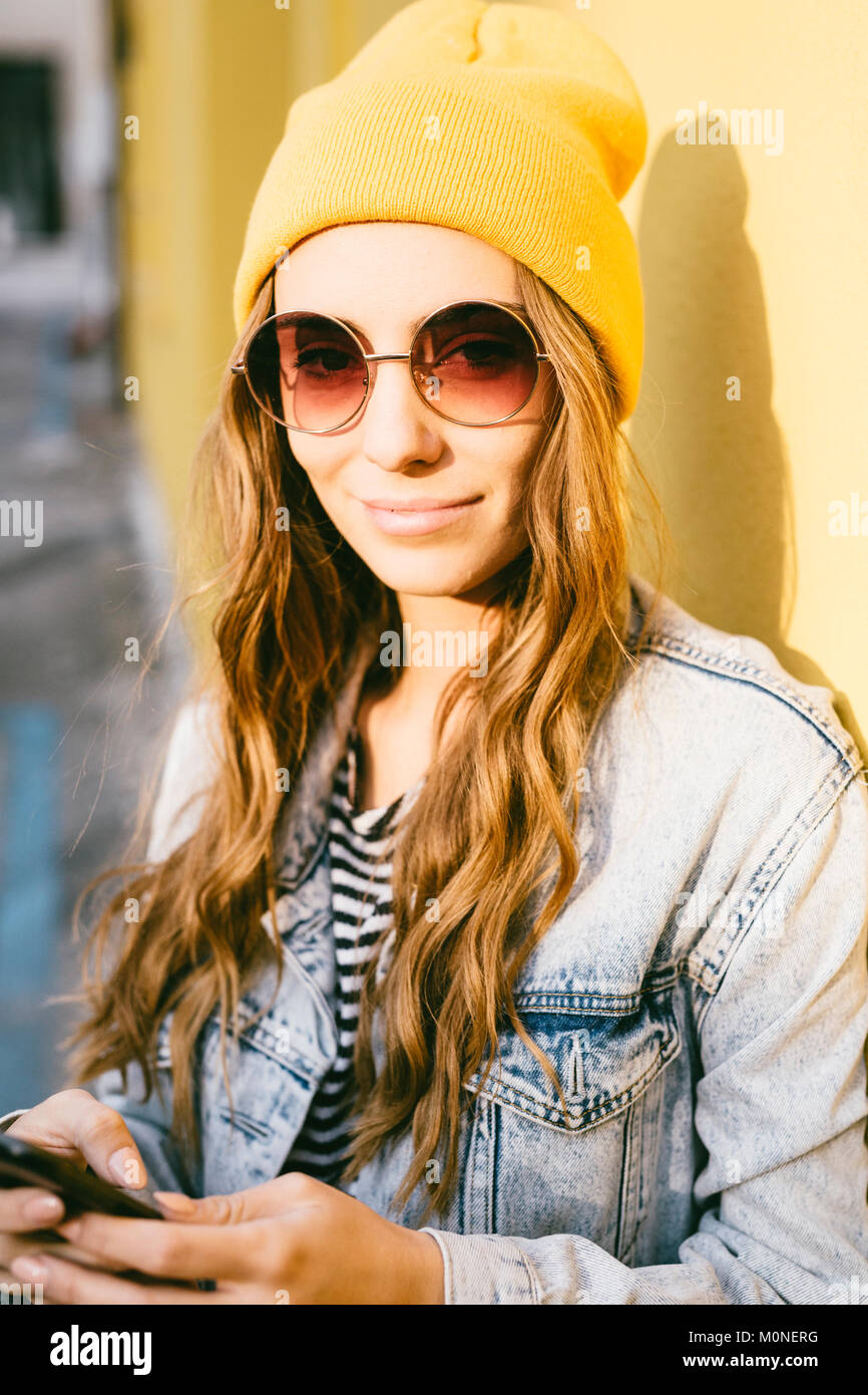 Portrait of fashionable young woman wearing yellow cap and sunglasses ...