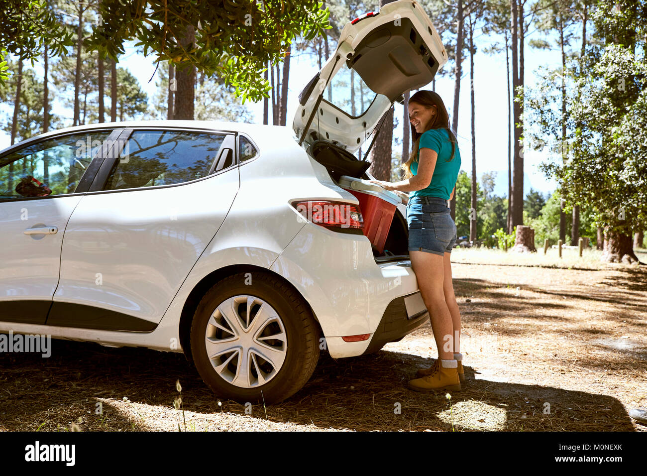 Smiling young woman loading a car Stock Photo - Alamy