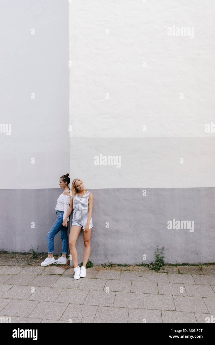 Two young women standing at the corner of a building Stock Photo - Alamy
