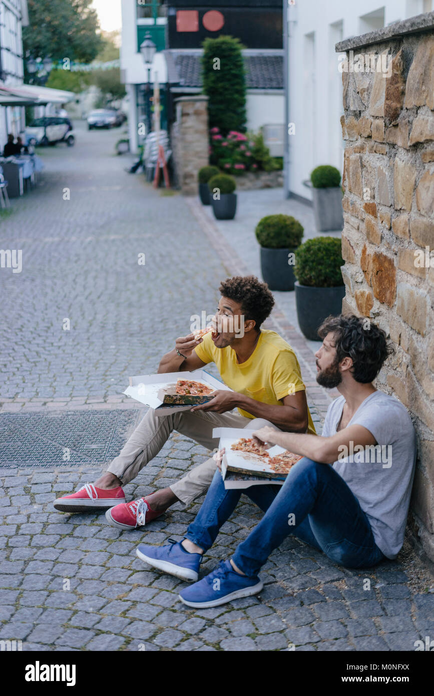 Two friends eating takeaway pizza in the city Stock Photo - Alamy