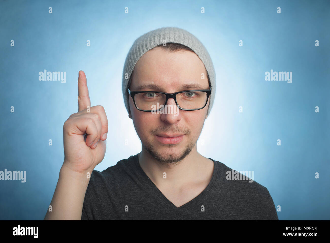 Portrait of smiling young man pointing upwards while standing against ...