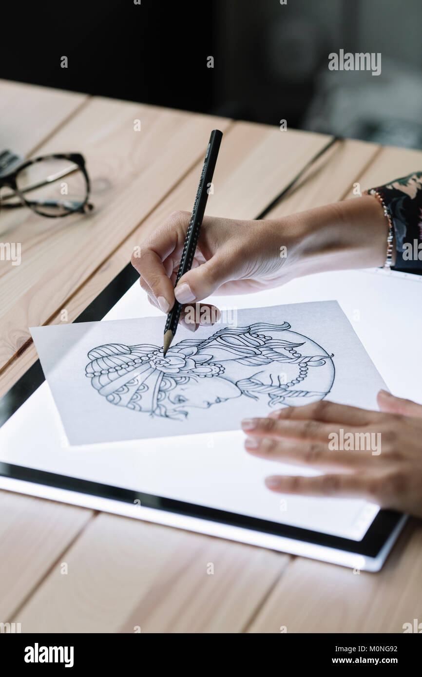 Woman's hand drawing template on light table Stock Photo - Alamy