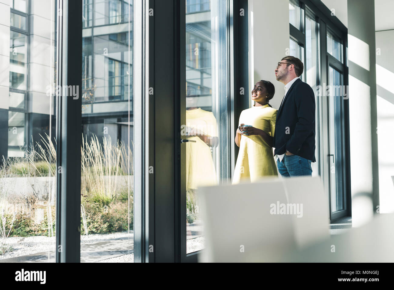 Colleagues looking out of the window in office Stock Photo - Alamy