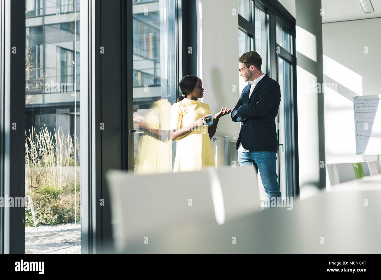 Colleagues talking at the window in office Stock Photo - Alamy