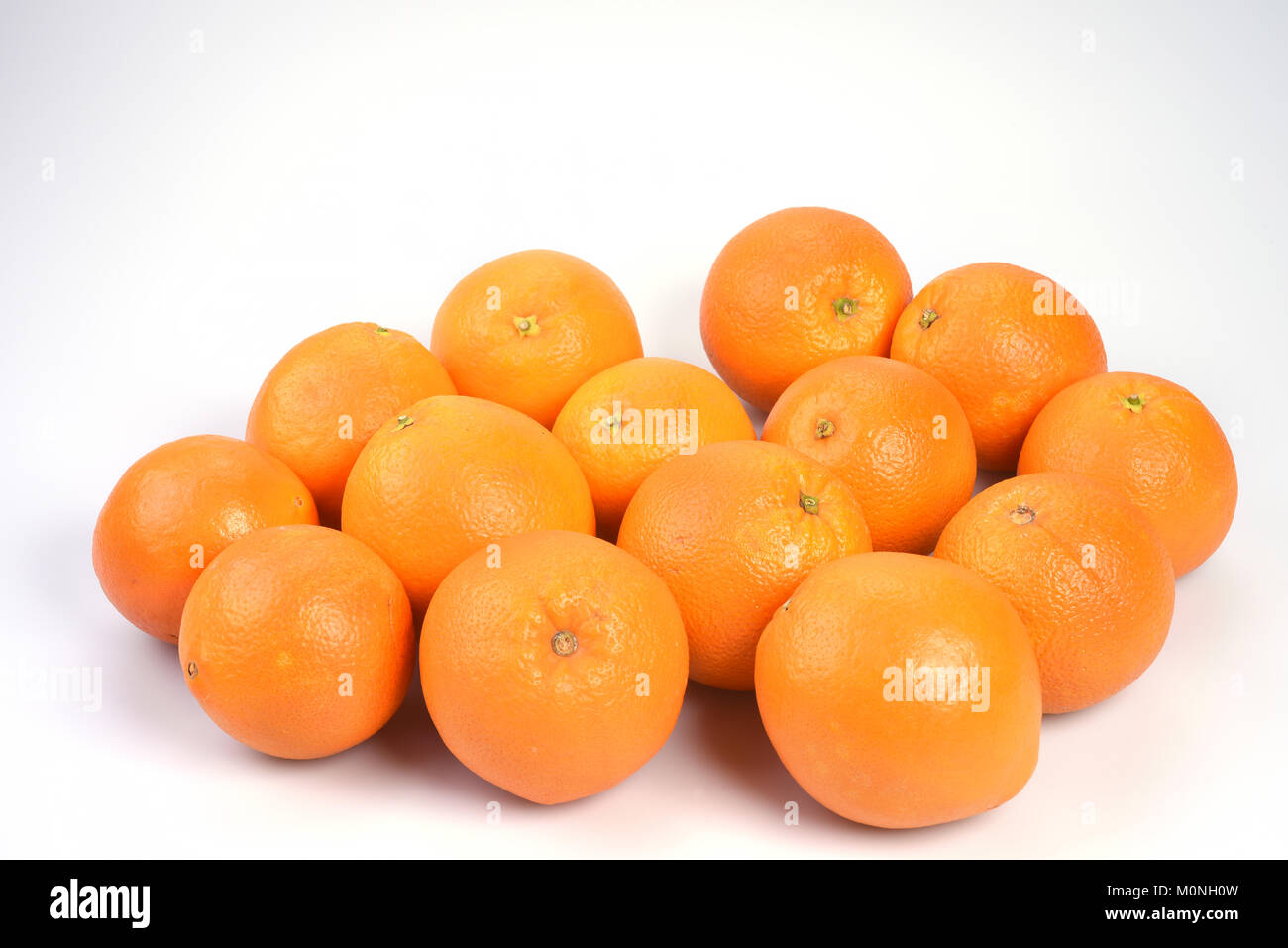 A lot of orange round fresh oranges lie in a pile on a white background ...