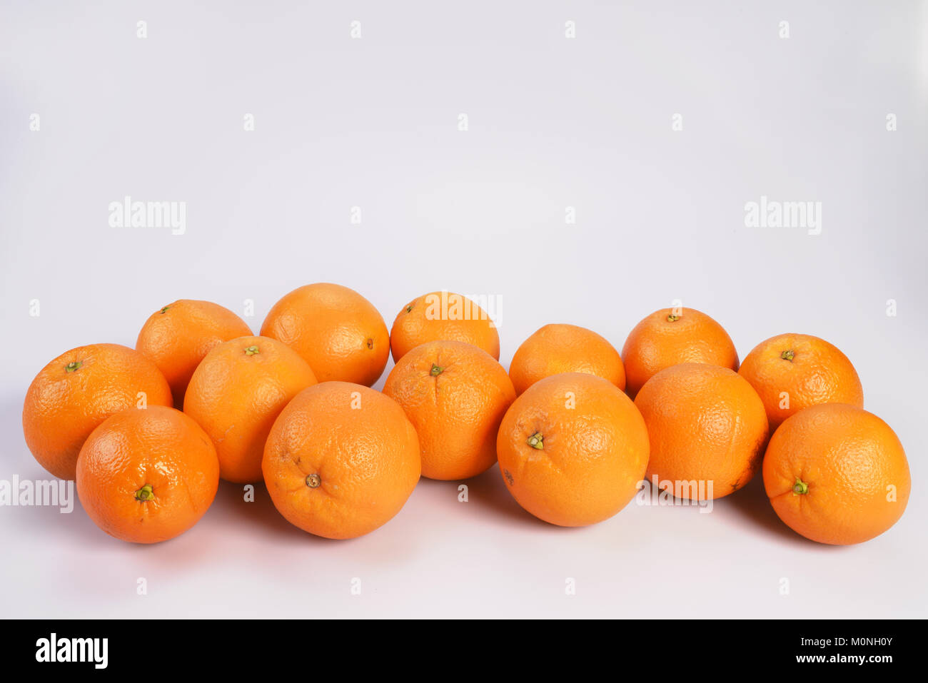 Orange shiny round oranges lie in a line on a white background, on top ...