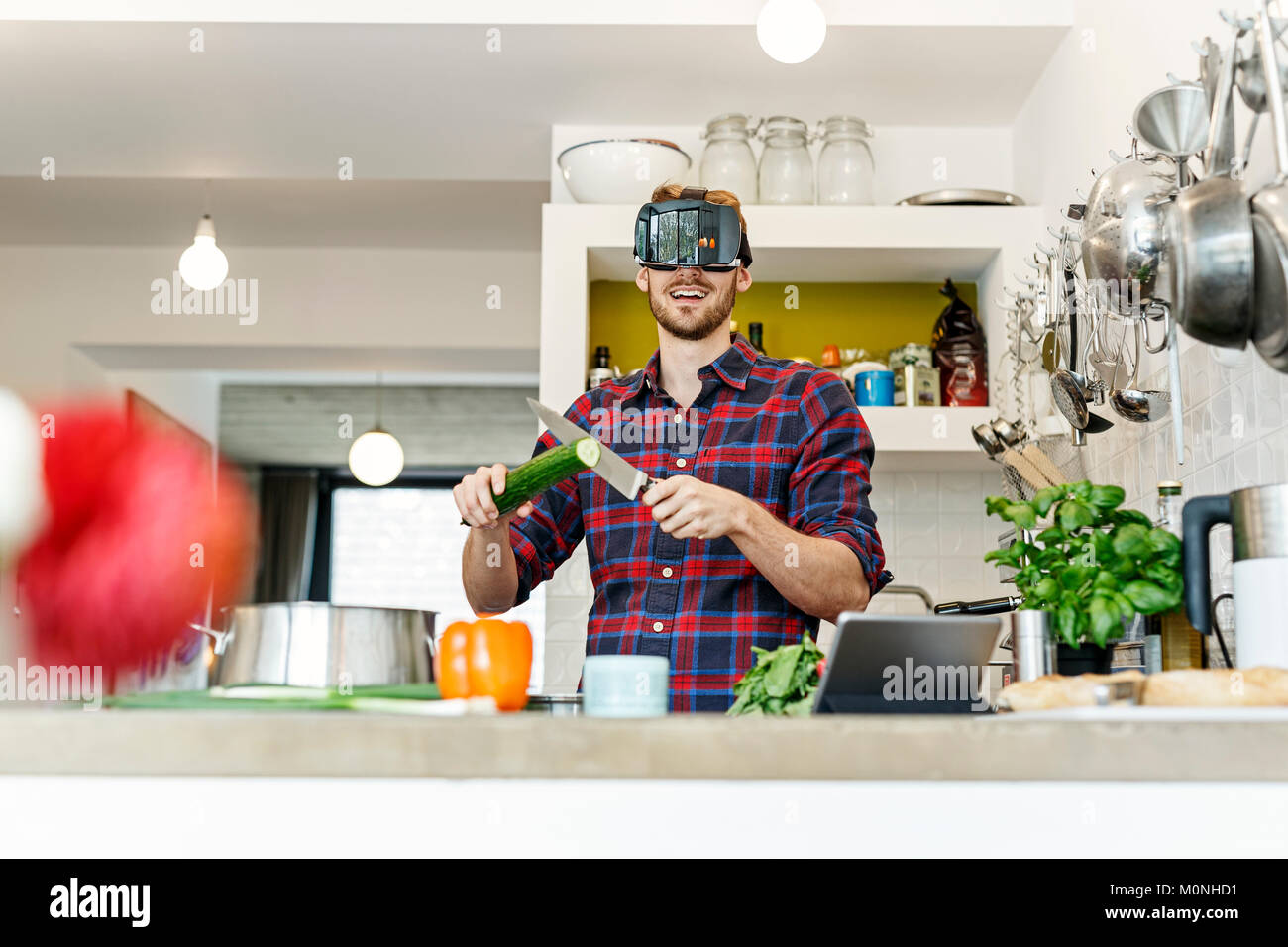 Happy young man wearing VR glasses cooking in kitchen Stock Photo - Alamy