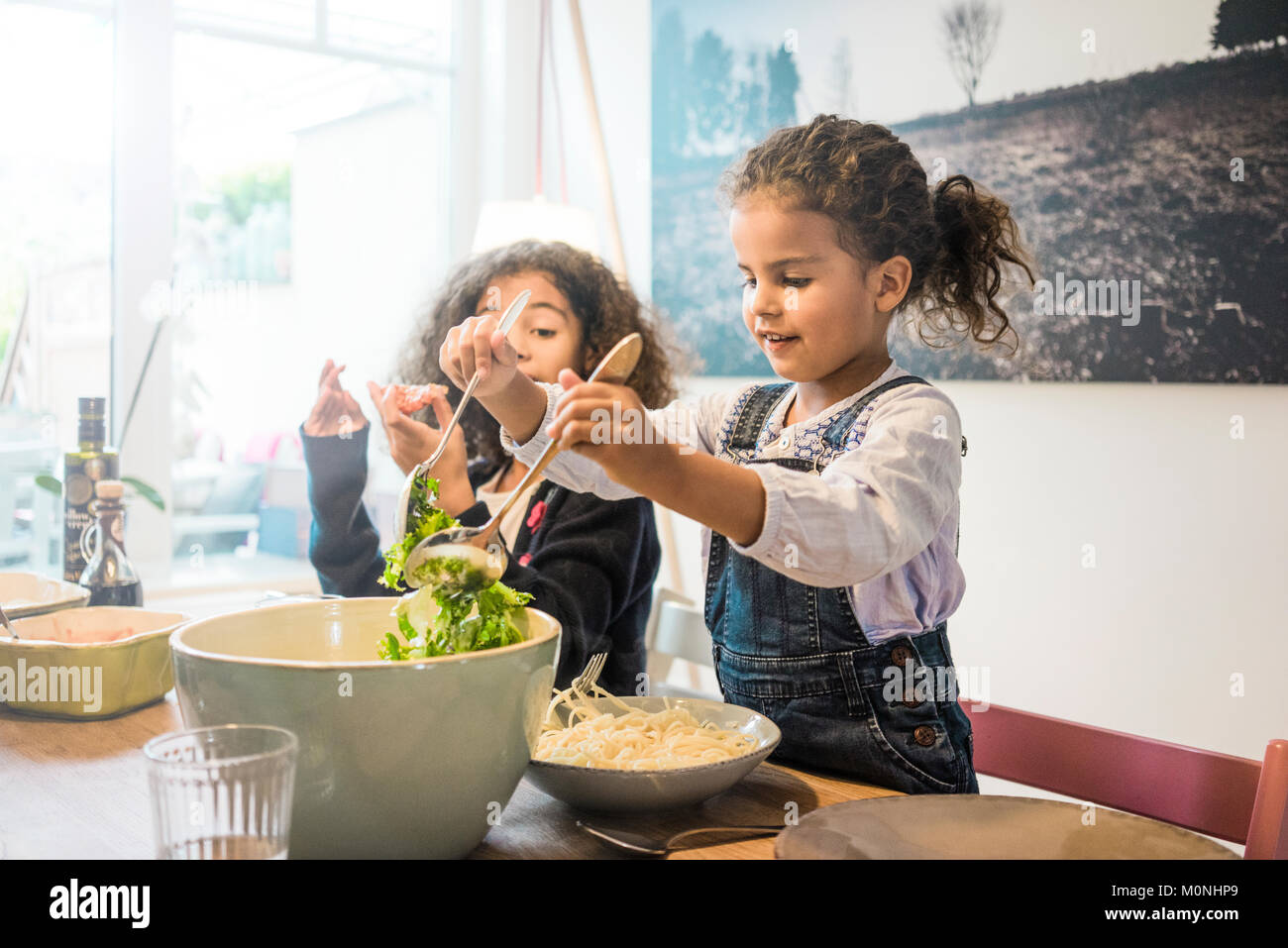 Happy family eating spaghetti, girl serving salad Stock Photo - Alamy