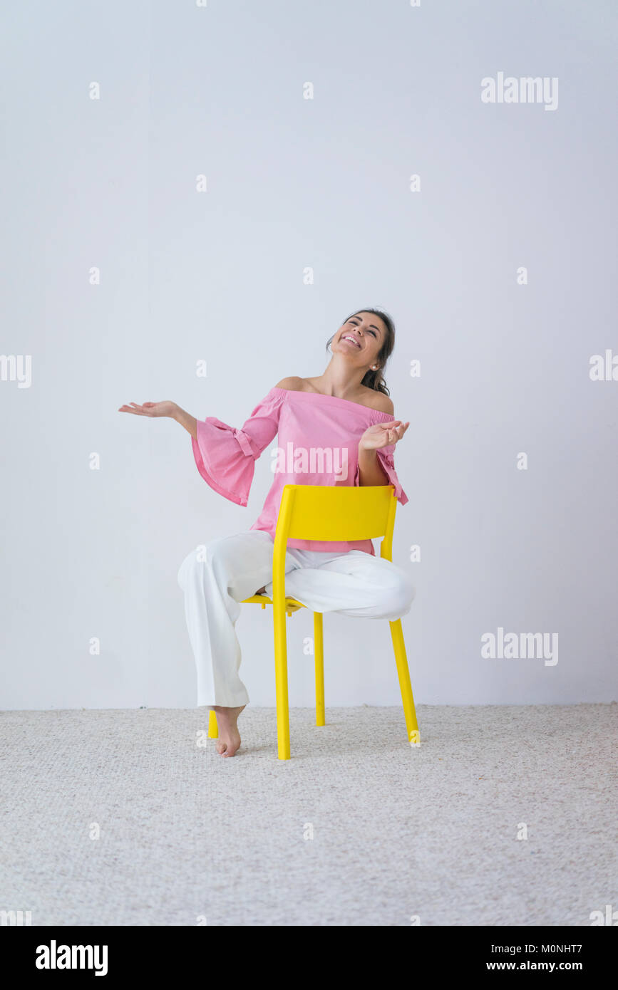 Portrait of laughing woman sitting on yellow chair Stock Photo - Alamy
