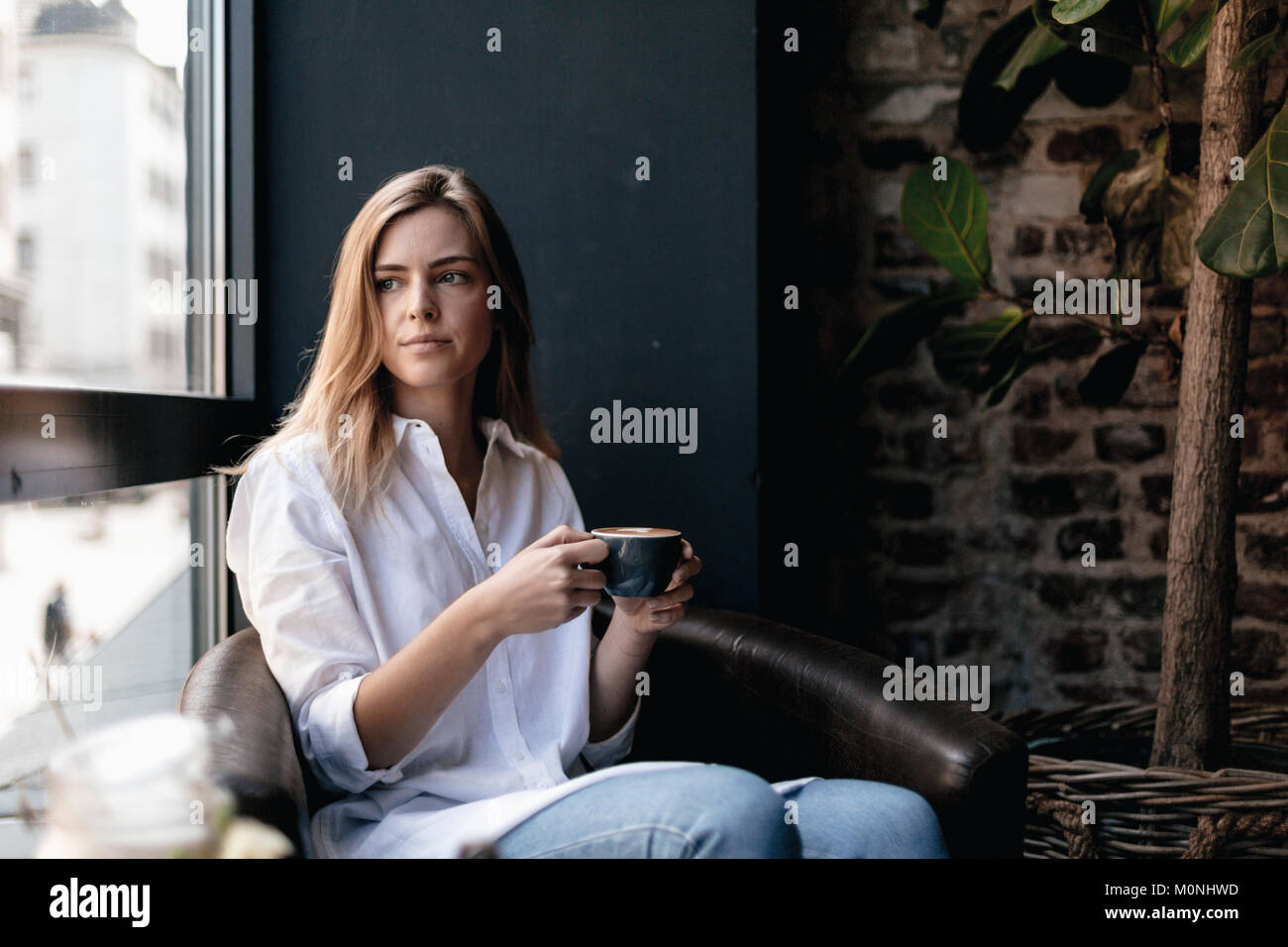 Young woman sitting in cafe, drinking coffee Stock Photo - Alamy