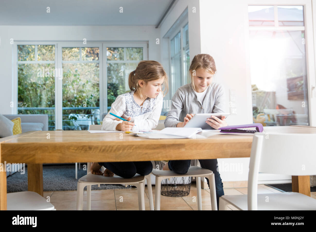 Two girls doing homework at table together using a tablet Stock Photo ...