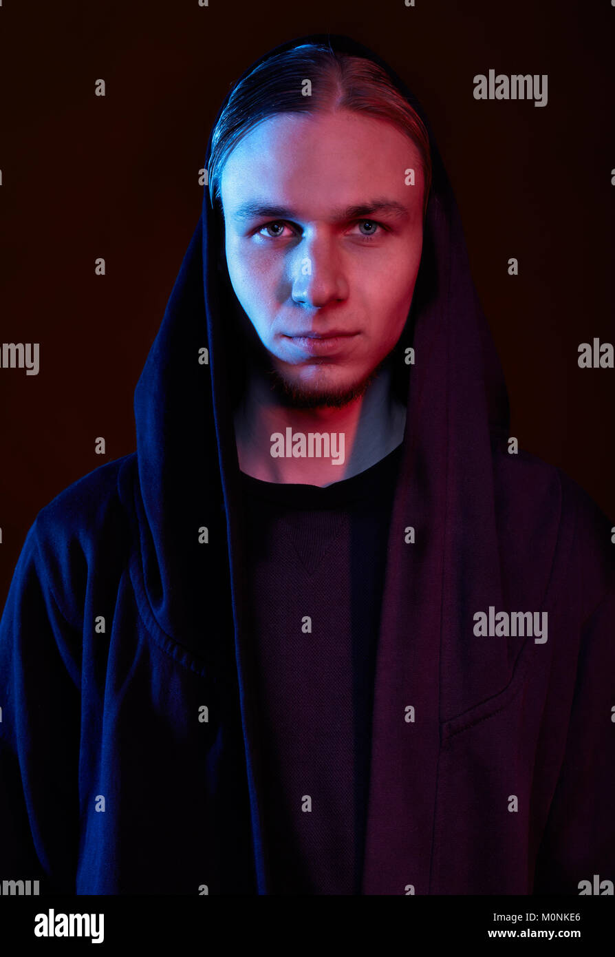 Young blond mystic man in hood on black background Stock Photo - Alamy