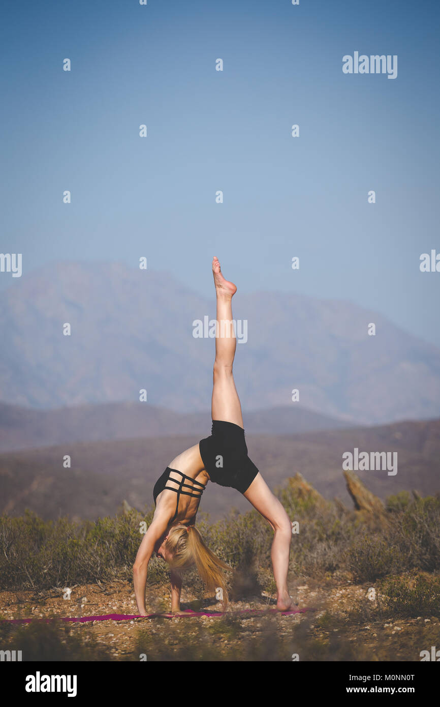 Female model practicing yoga in the outdoors doing stretching and ...